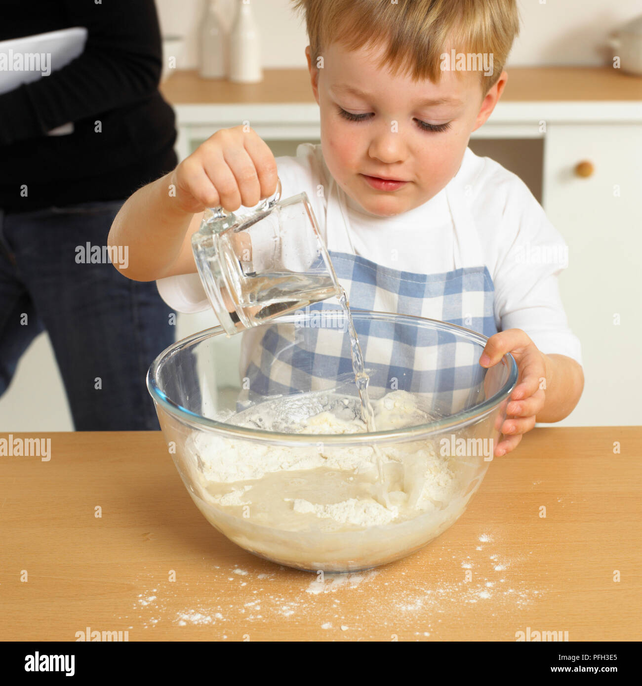 Boy pouring water from jug into bowl Stock Photo - Alamy