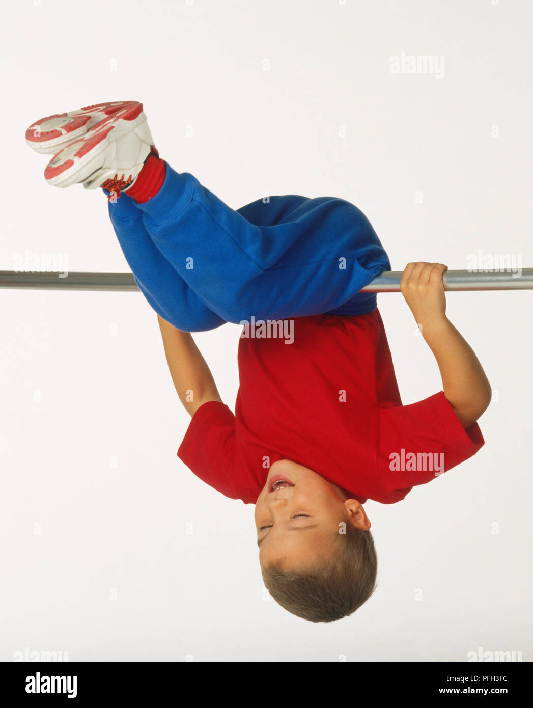 Boy lifting himself up on a bar with his legs forward, front view Stock ...
