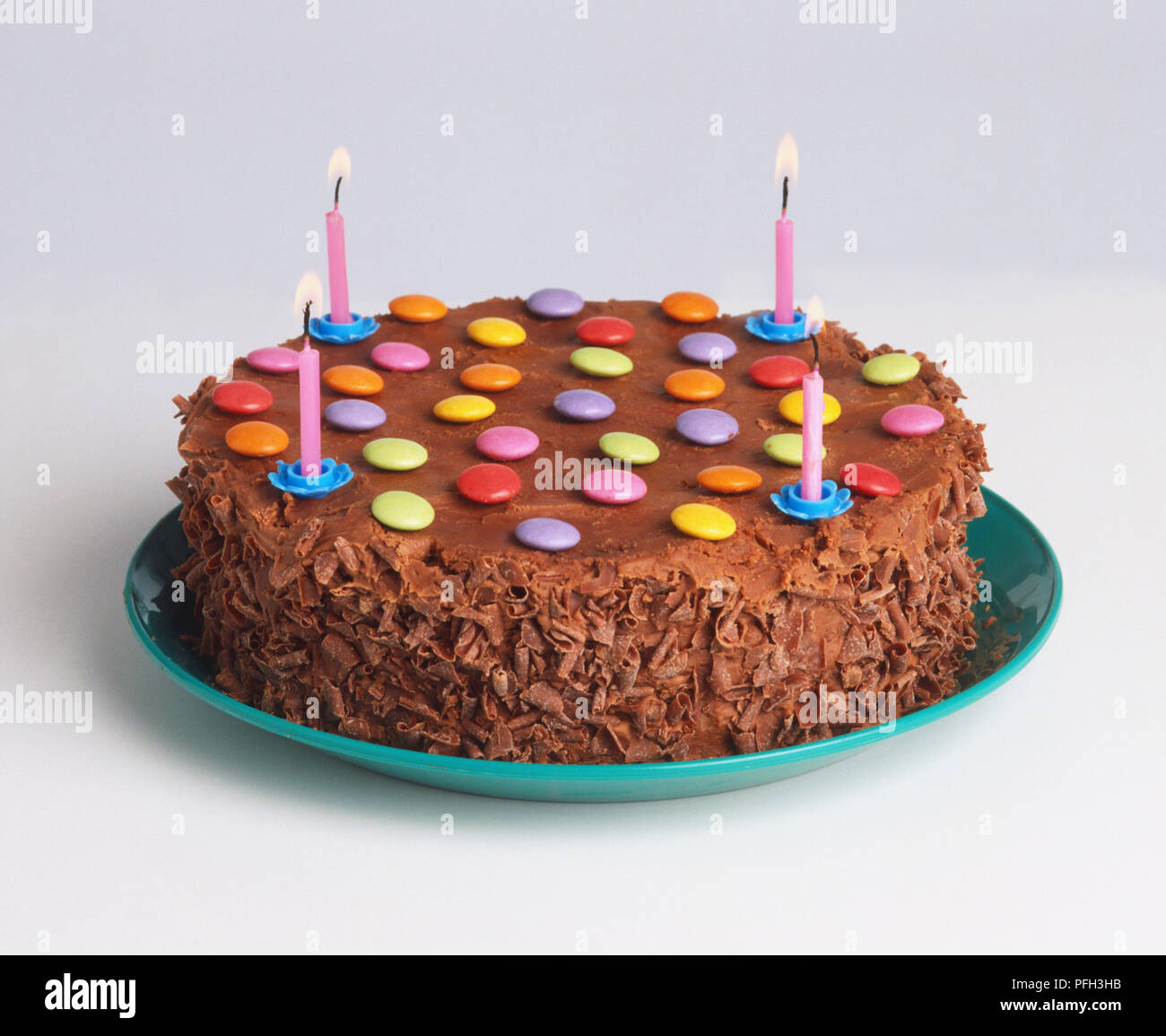 Birthday chocolate cake decorated with colourful candy and four candles ...