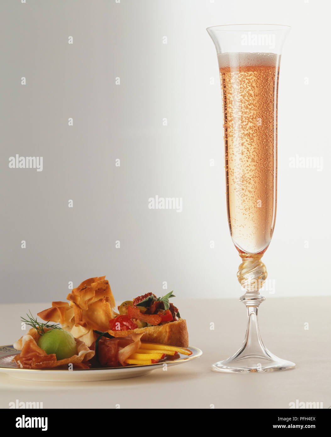 A tall glass of champagne and a plate of canapes Stock Photo - Alamy