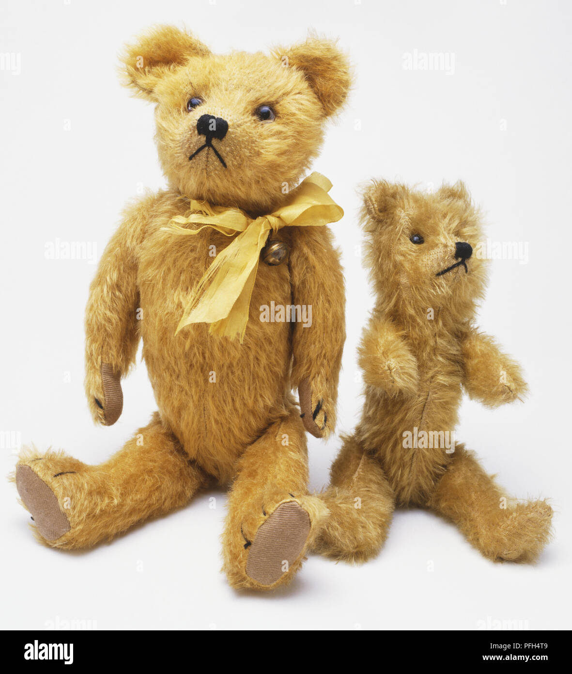 Two teddy bears sitting side by side, larger one wearing bow tie,side ...