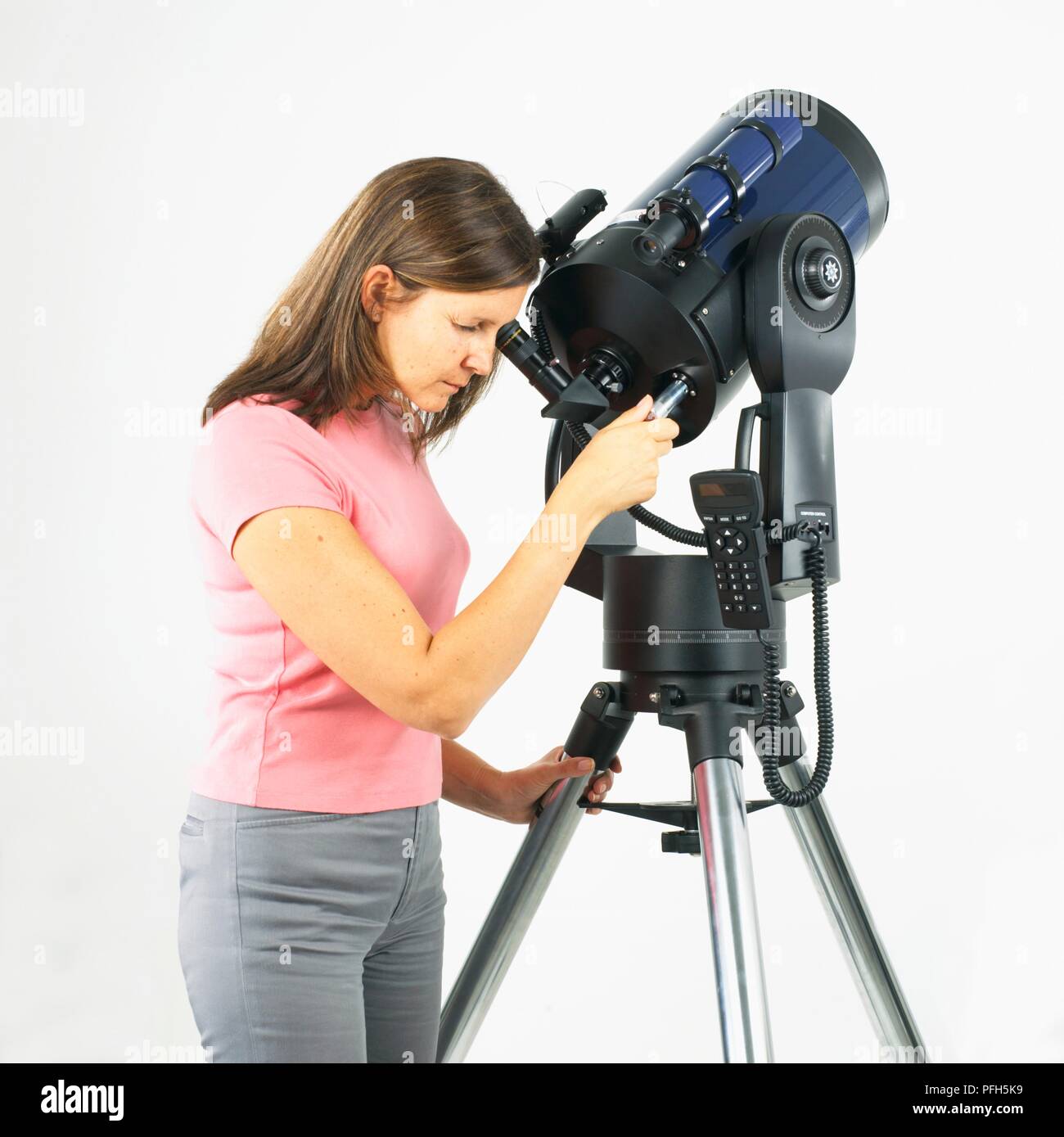 Woman looking into eyepiece of computerised telescope while adjusting ...