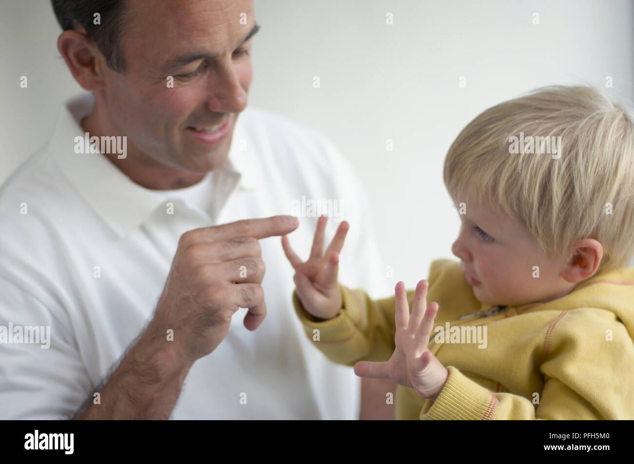 Man touching tips of boy's outstretched fingers Stock Photo - Alamy