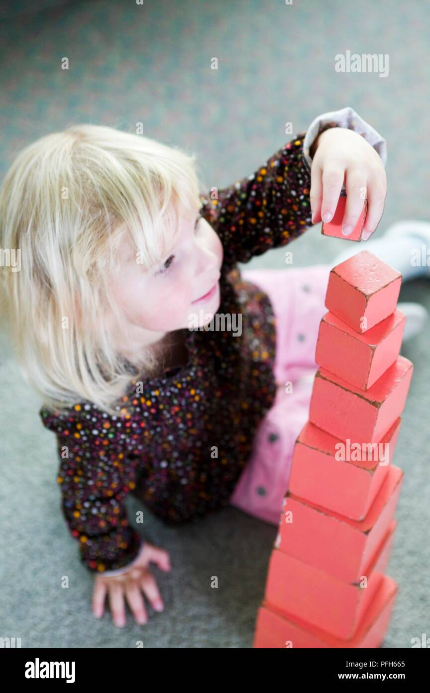 Girl stacking red wooden blocks in size order Stock Photo - Alamy