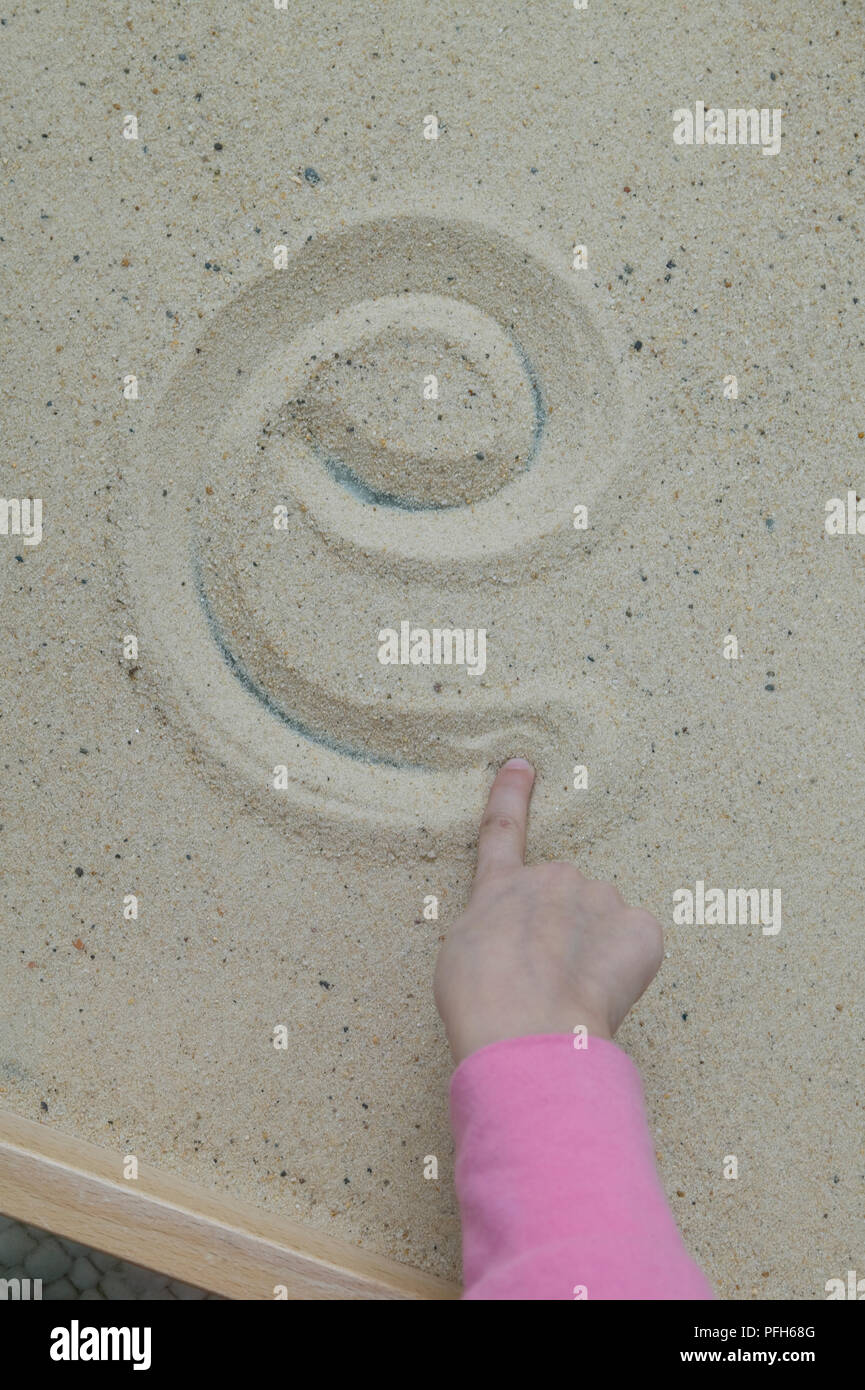 Child writing small letter 'e' in sand Stock Photo - Alamy