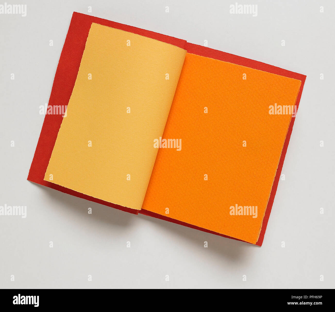 Red blank notebook, open to yellow and orange pages, close-up Stock ...