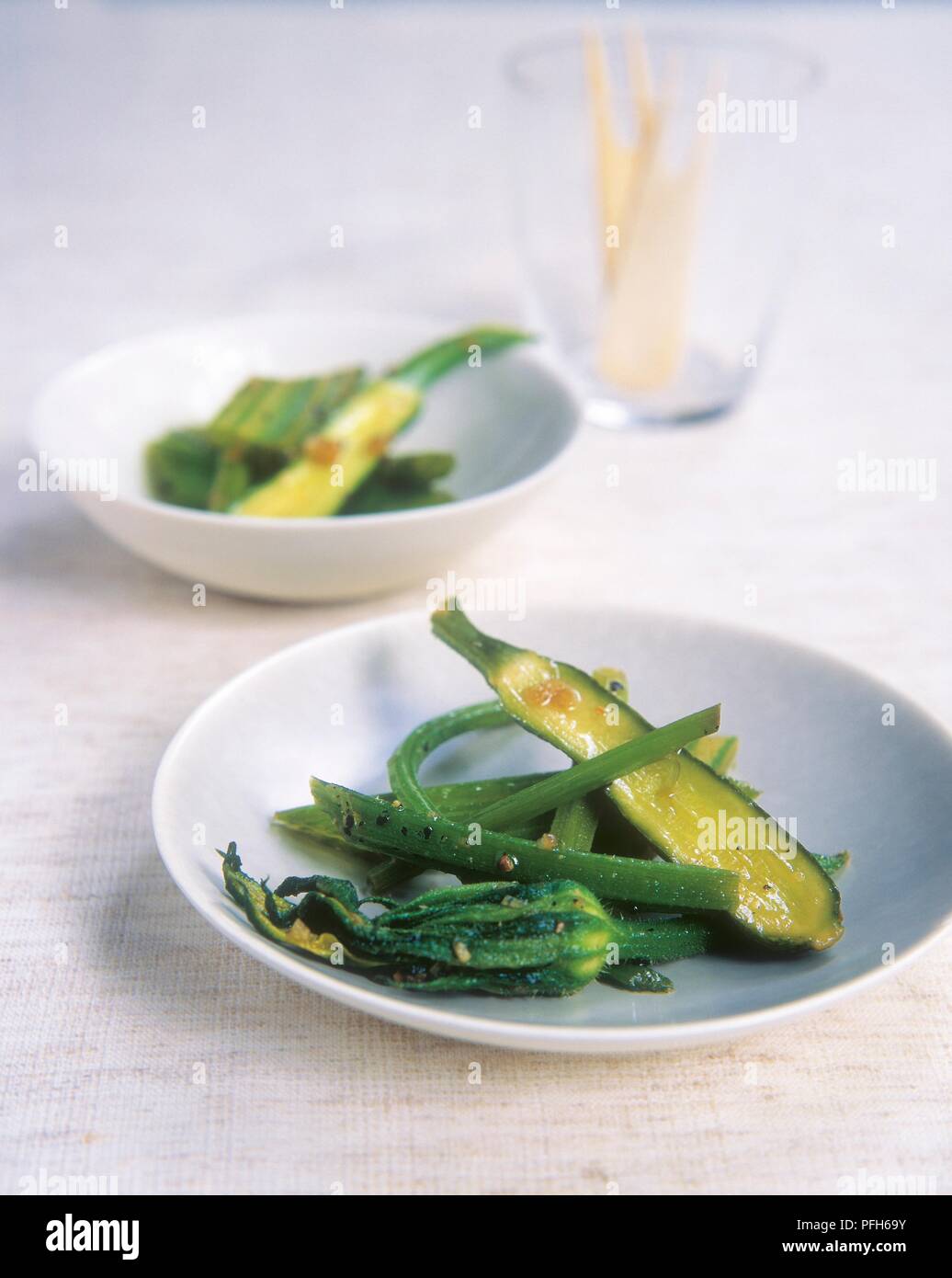 Bowls of stir-fried greens with garlic and a glass containing small ...