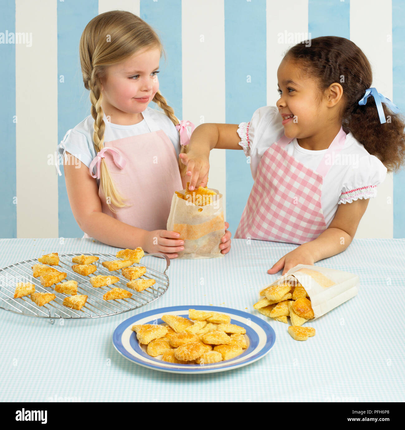 Two girls, one holding bag of cheese biscuits, the other with one hand ...