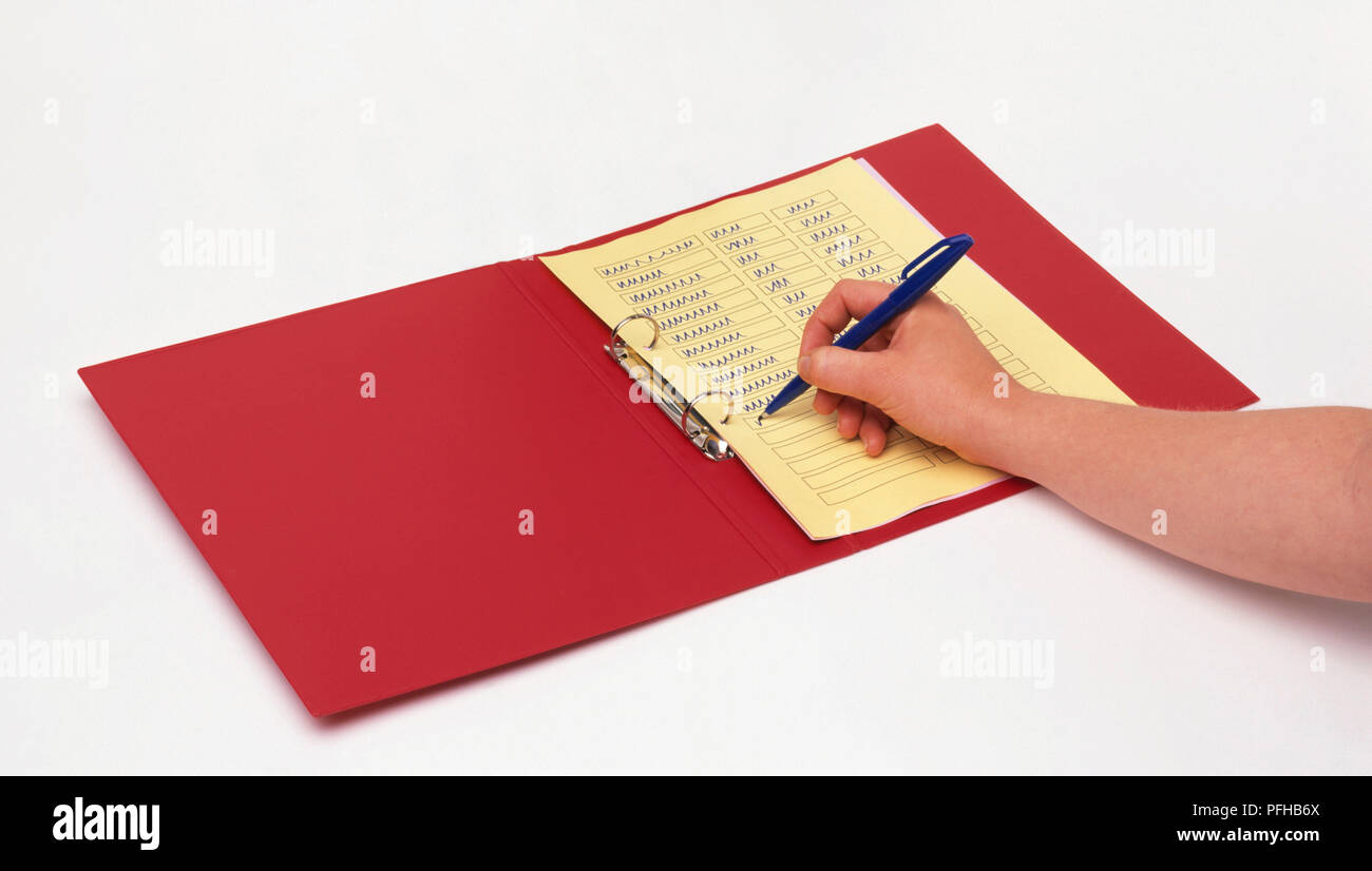 Person writing a list on a sheet of paper in a ring binder, close-up ...