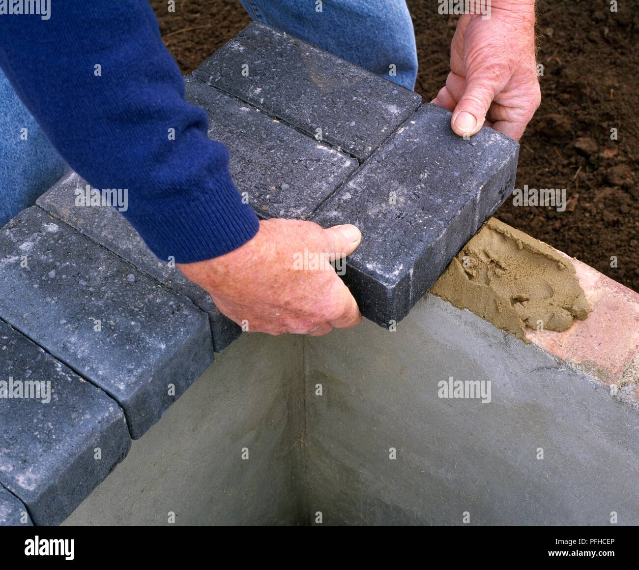 Cementing bricks on top of wall Stock Photo - Alamy