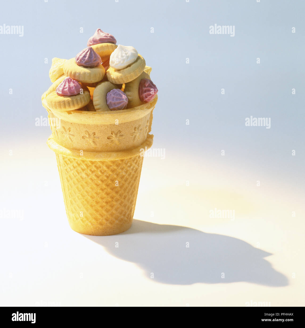 Wafer ice cream cone filled with iced sweets mini biscuits, close up ...