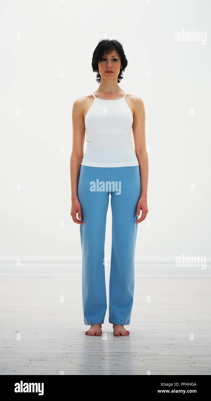 Woman standing upright, hands beside body, feet slightly apart, facing ...