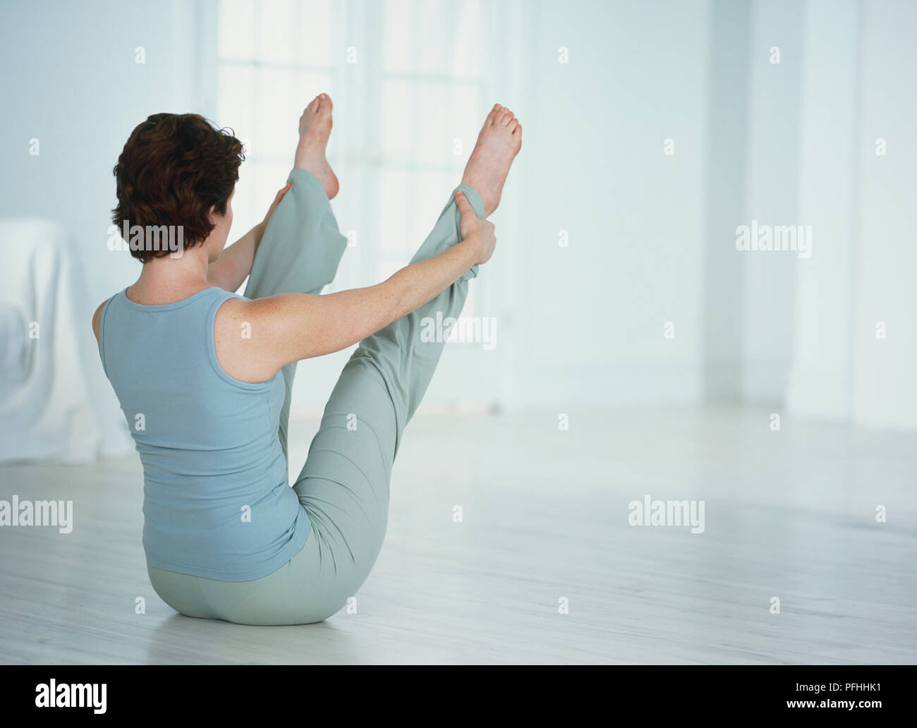 Woman holding her ankles, balancing on her buttocks Stock Photo - Alamy