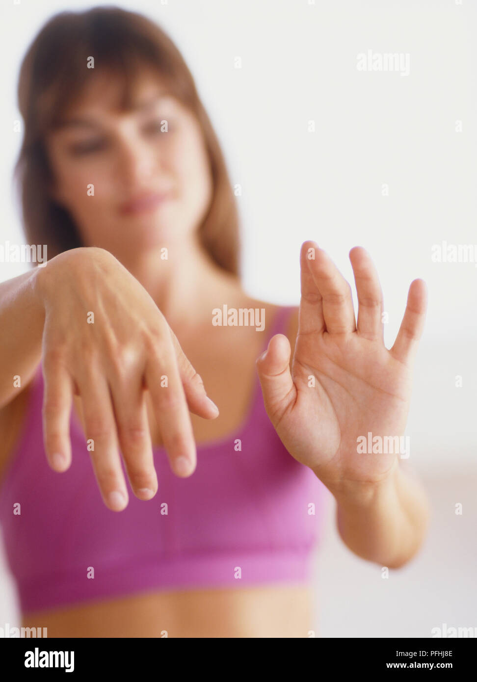 Woman in pink sports bra extending her arms forward and bending her ...