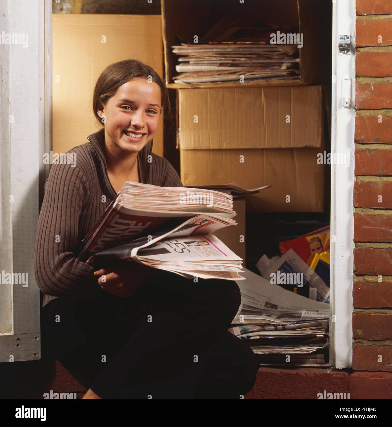 Girl crouching sitting in a door frame newspapers Stock Photo - Alamy
