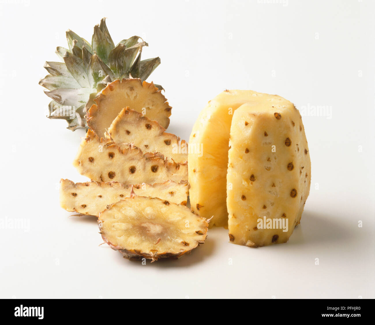 Peeled pineapple with section removed displayed next to its skin, close ...