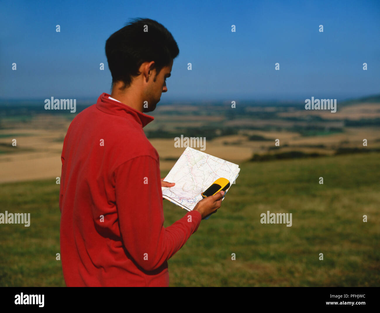 Man reading a map with a GPS, flat landscape ahead Stock Photo - Alamy