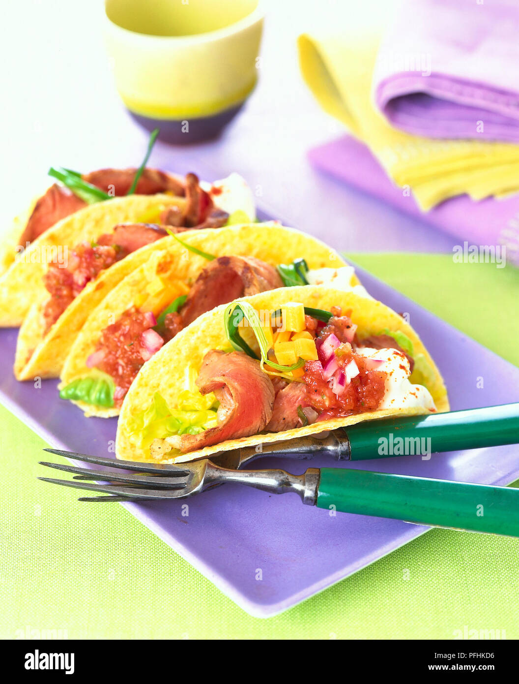 Soft-shell steak tacos served with forks on rectangular plate, close up ...