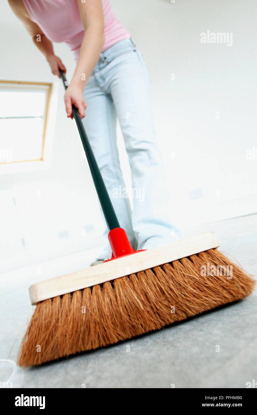 Woman sweeping floor with broom Stock Photo - Alamy