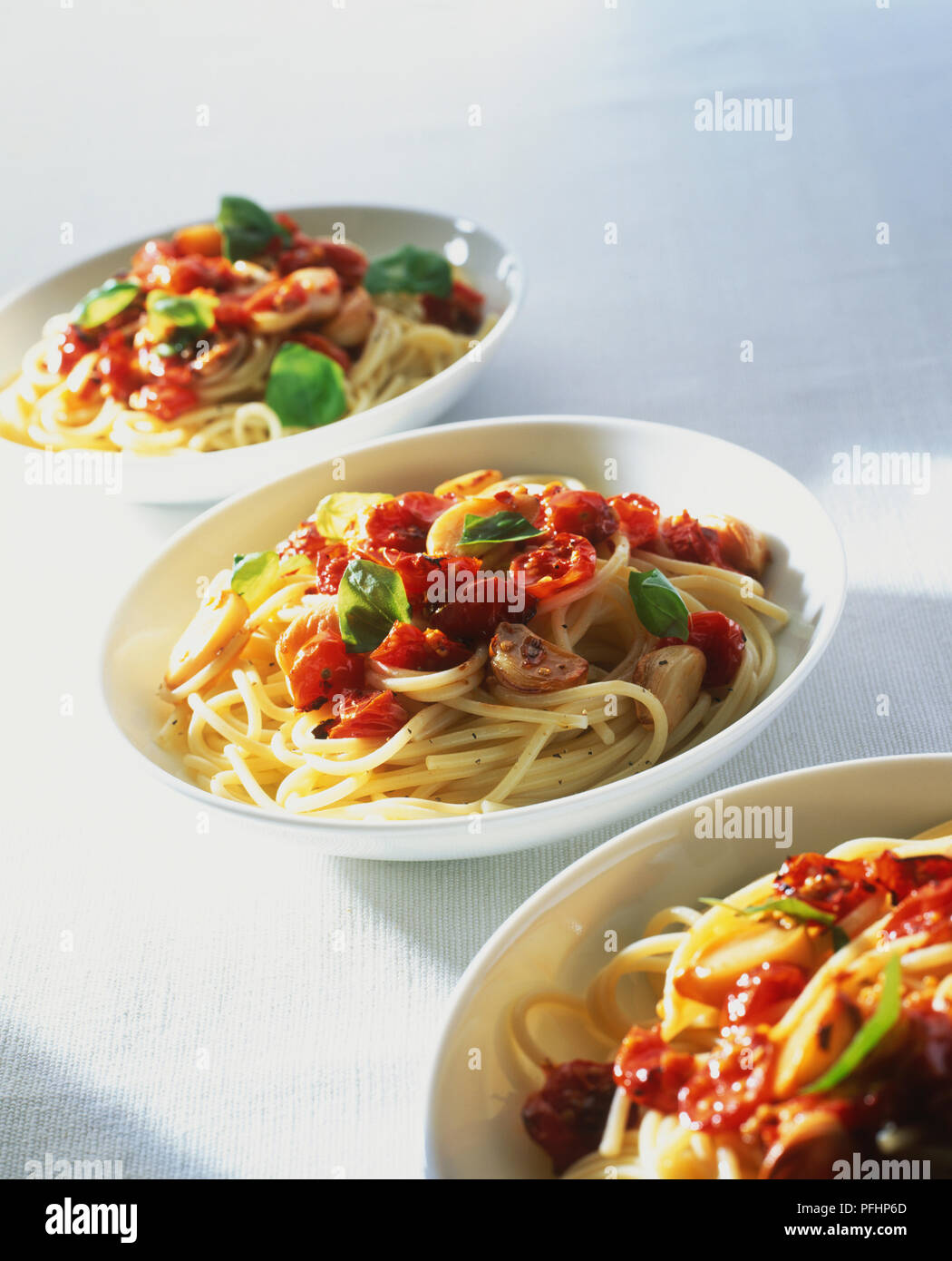 Three bowls of spaghetti topped with vegetables and herbs Stock Photo ...