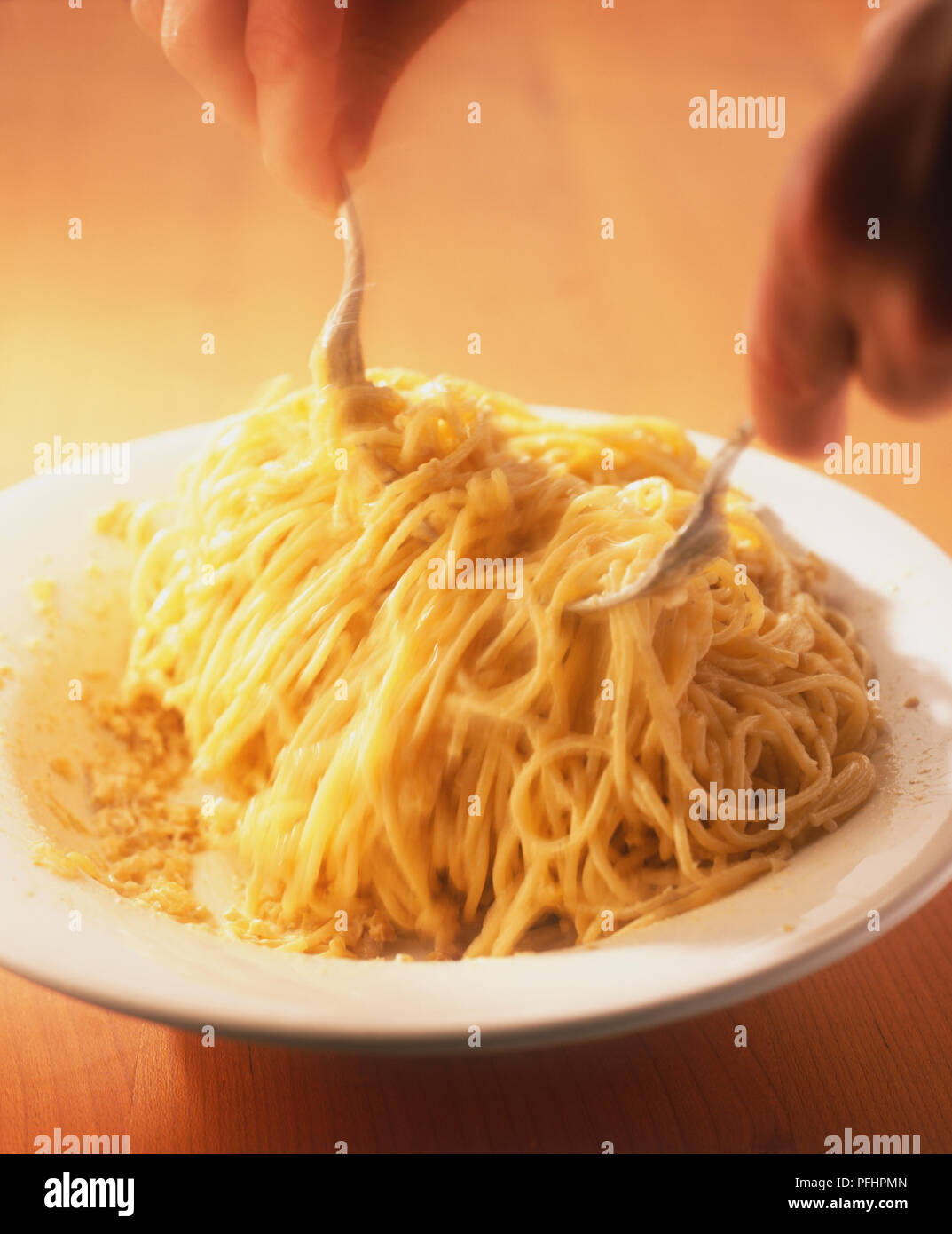 Spaghetti being tossed in a cream sauce with two forks Stock Photo - Alamy