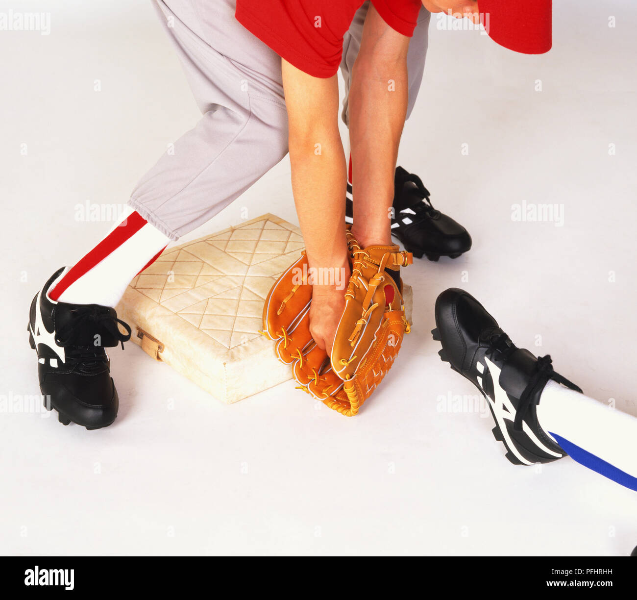 Boy wearing baseball uniform, cap, holding fielders mit, bending ...