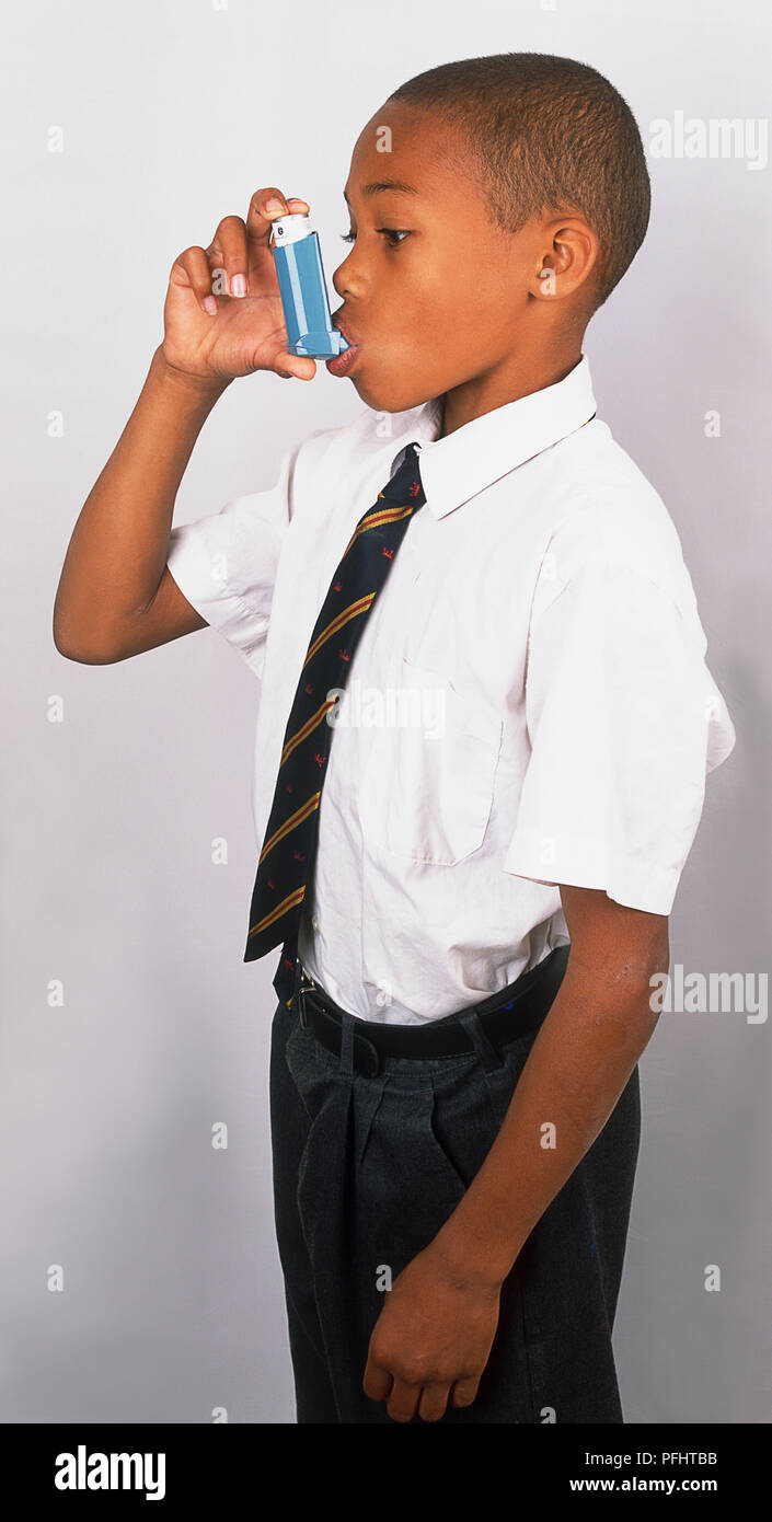 Boy in school uniform inhaling from asthma pump, side view Stock Photo ...