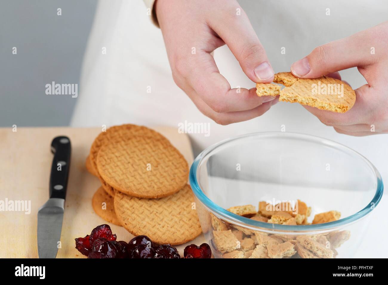 Using finger to break digestive biscuit over glass bowl Stock Photo - Alamy