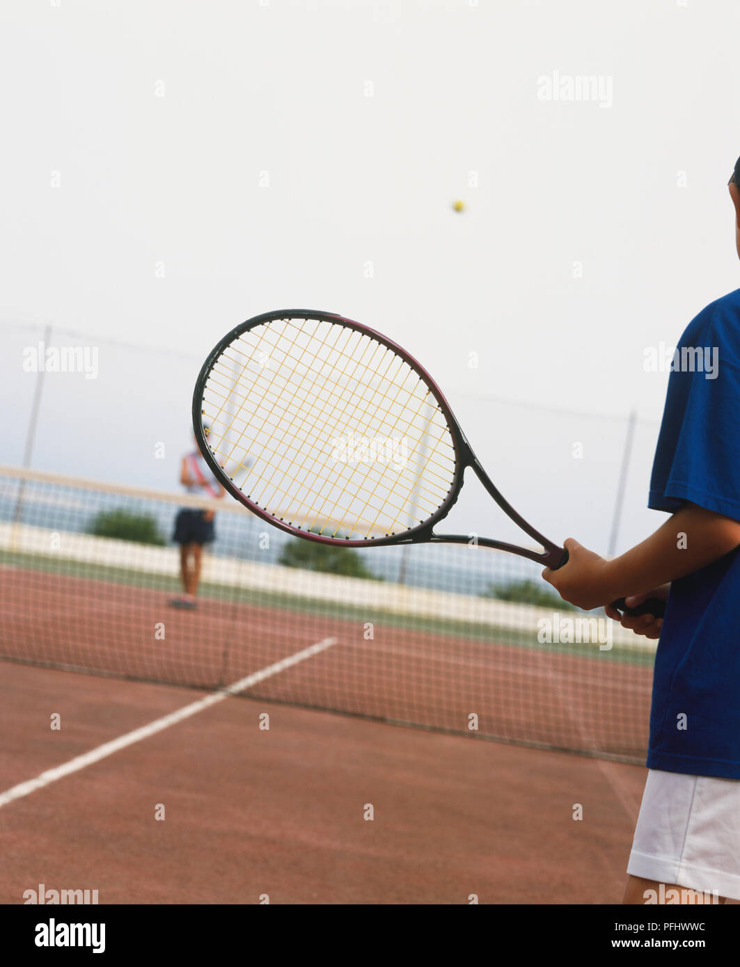 Boy holding tennis racket ready to hit ball flying at him from the ...