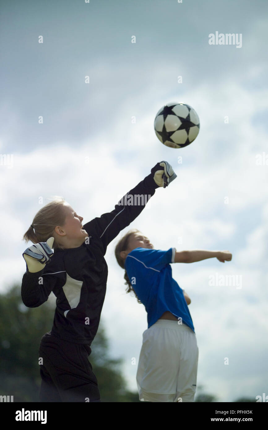 Goalkeeper punching the ball away from a blue attacking player Stock ...