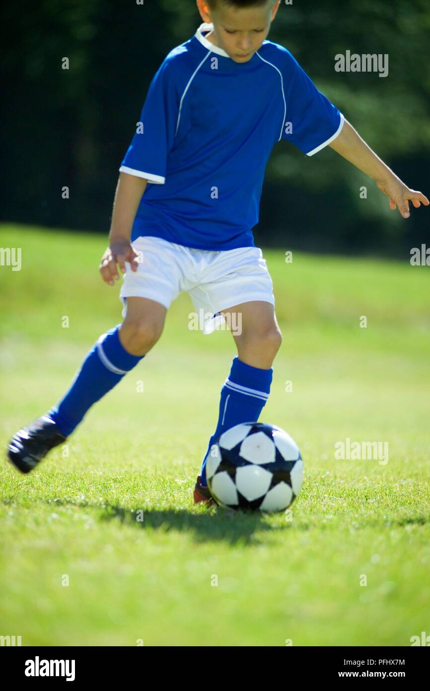 Boy in blue football shirt performing a side foot pass, close-up Stock ...