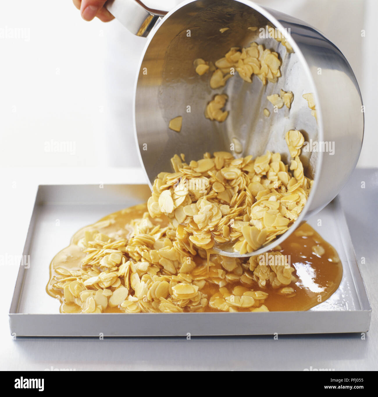 Pouring almond flakes, sugar and lemon juice mixture into an oiled pan ...