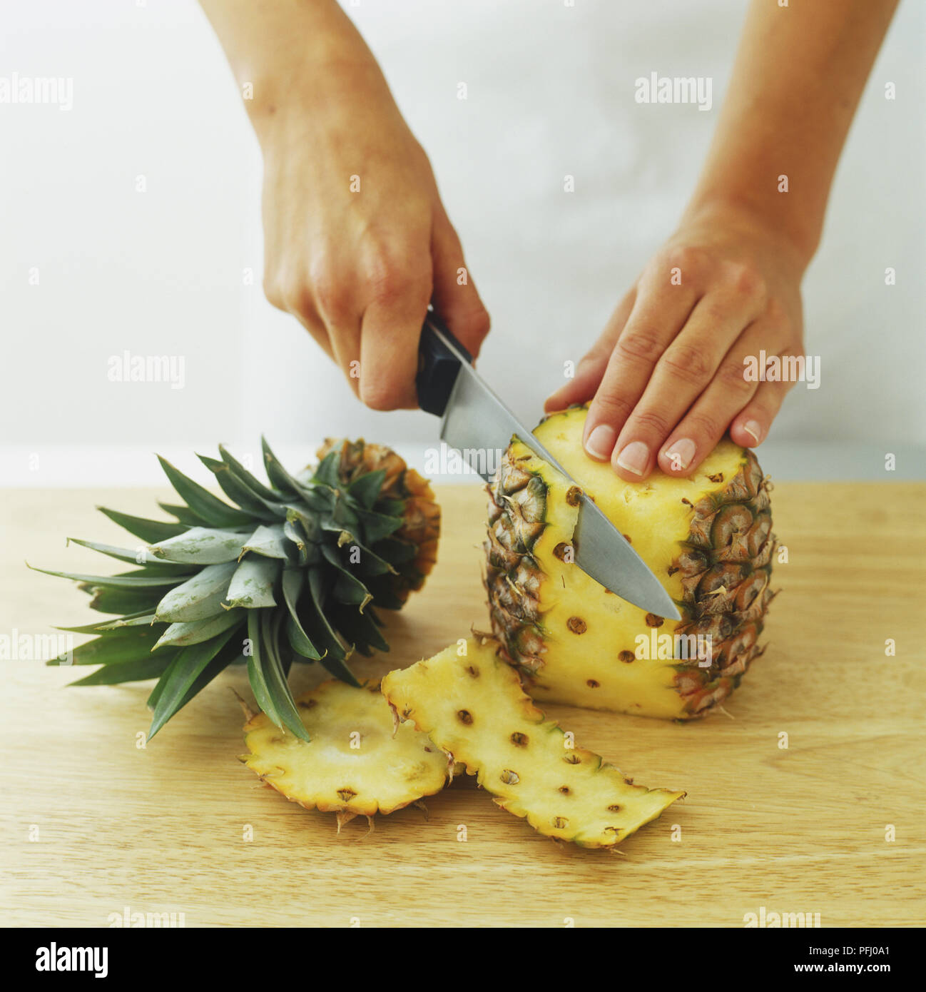 Slicing off stalky top and skin of a pineapple Stock Photo - Alamy