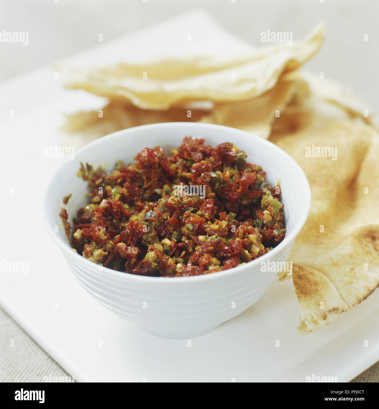 Bowl of tomato tapenade sauce served with crispy breads, close up Stock ...