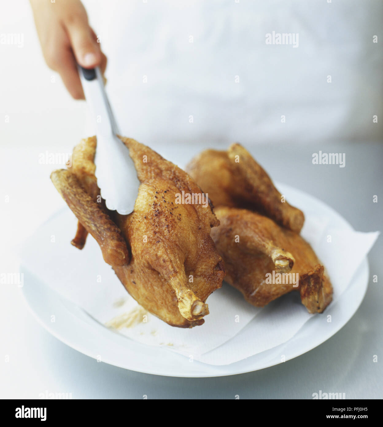 Using tongs to place fried chicken on kitchen paper Stock Photo - Alamy