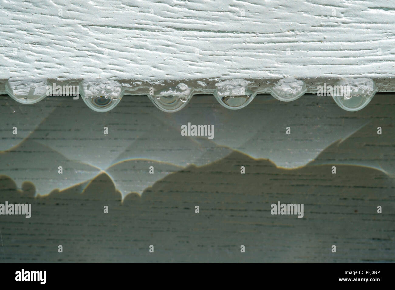 Water drops on edge of garden table with sunlight refracted through the ...