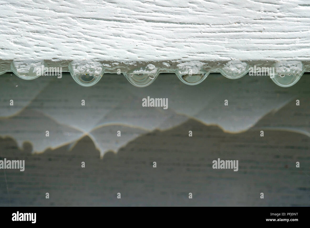WATER DROPS ON UNDERSIDE OF WOODEN GARDEN TABLE With REFRACTED LIGHT ...