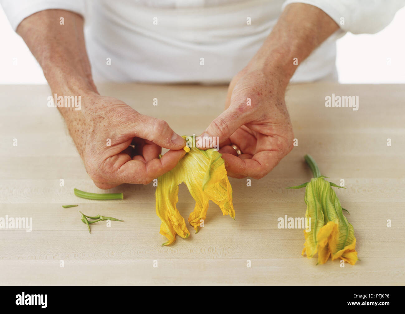 Preparing courgette flowers by pulling sepals from around base and ...