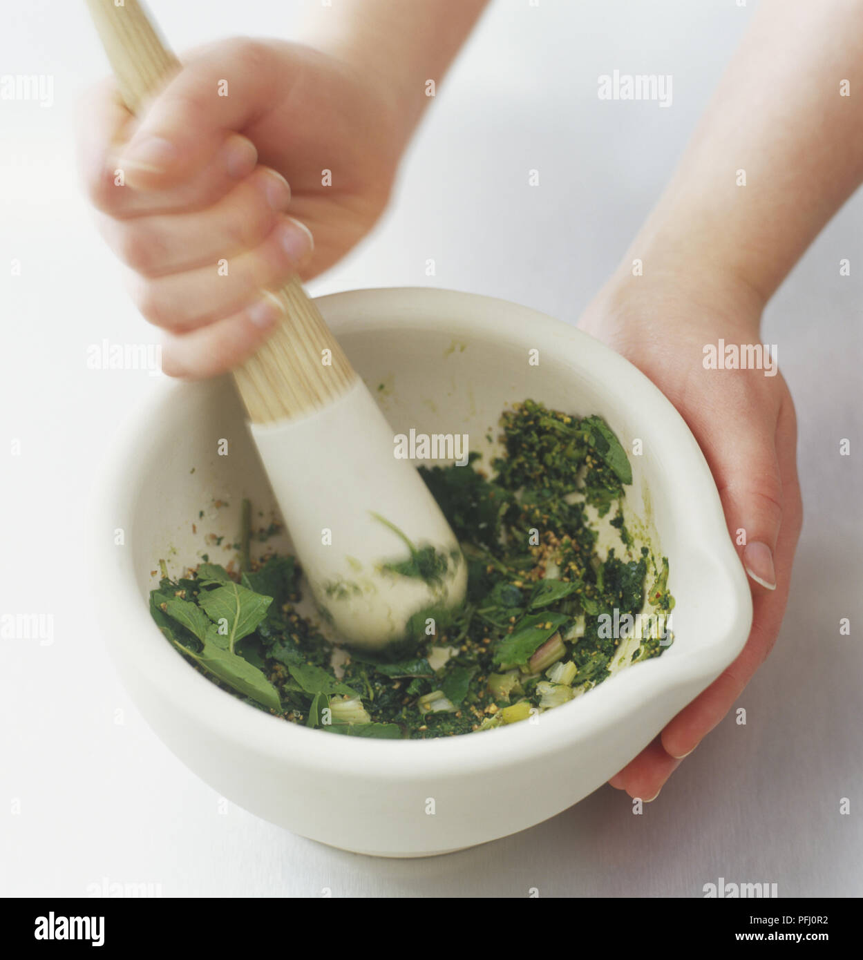 Using pestle and mortar to pound mixture of herbs Stock Photo - Alamy