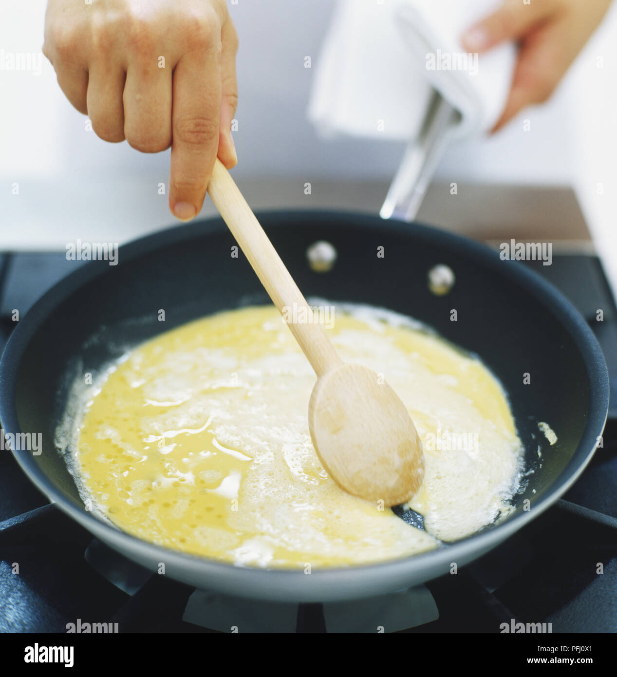 Stirring egg mixture with wooden spoon, side view Stock Photo - Alamy