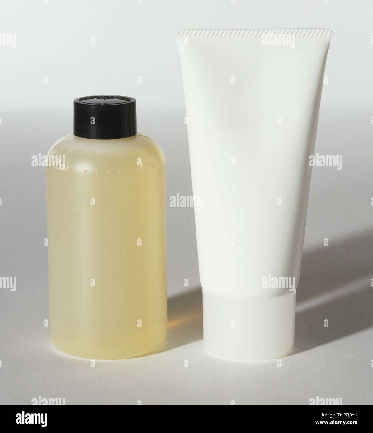 White hand cream tube and semi-transparent plastic bottle containing ...