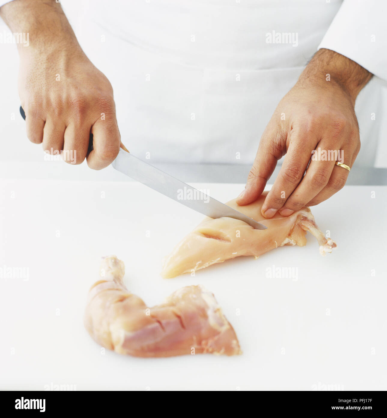 Using a sharp knife to make deep incisions to the bone of a chicken ...