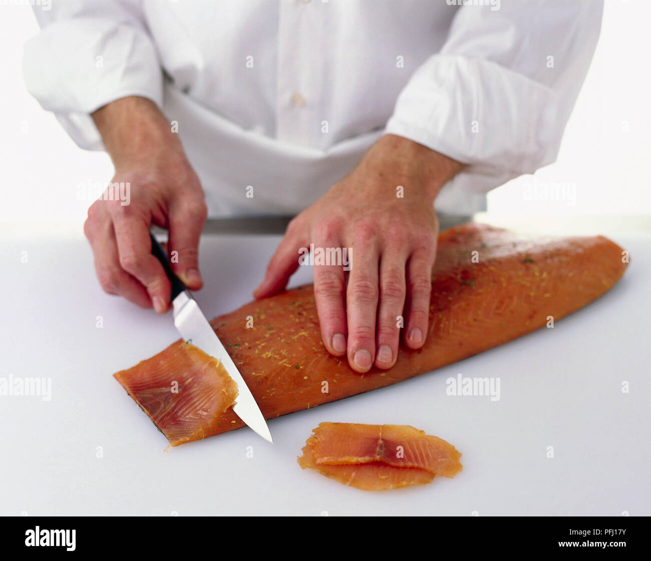 Cutting a fillet of cured salmon into thin, diagonally cut slices Stock ...