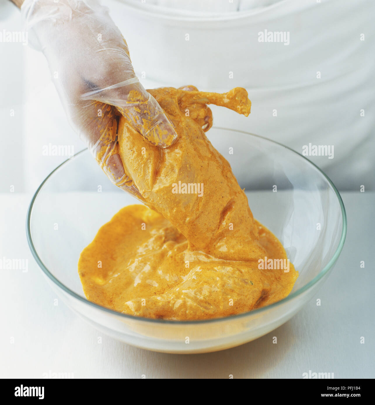 Coating chicken in curry marinade Stock Photo - Alamy