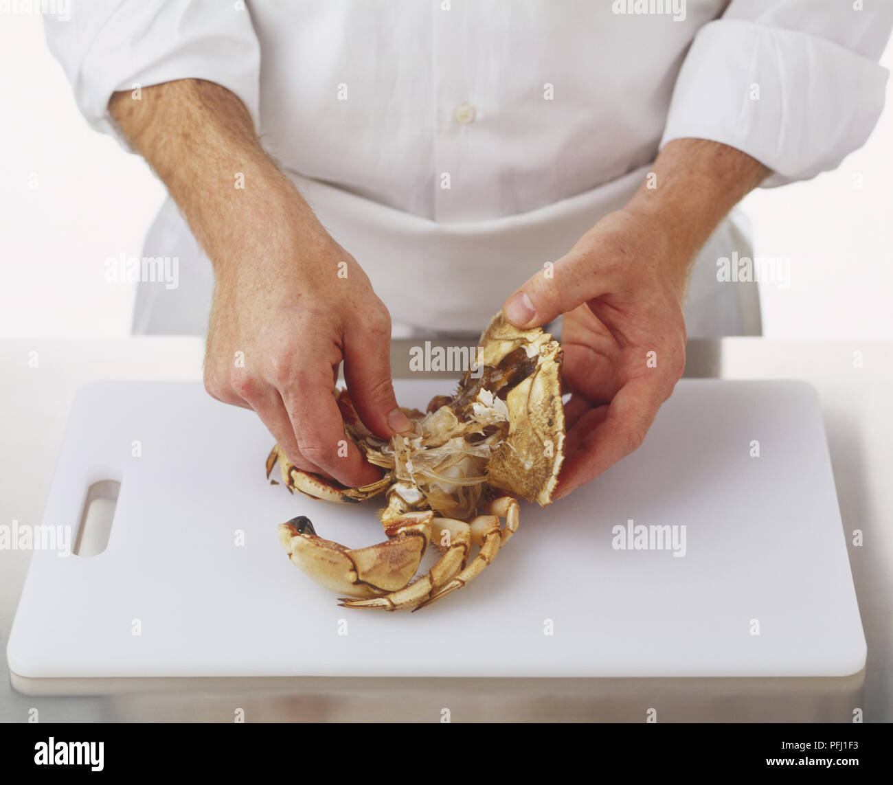 Cleaning a live blue crab, pressing down on centre and leg section and ...