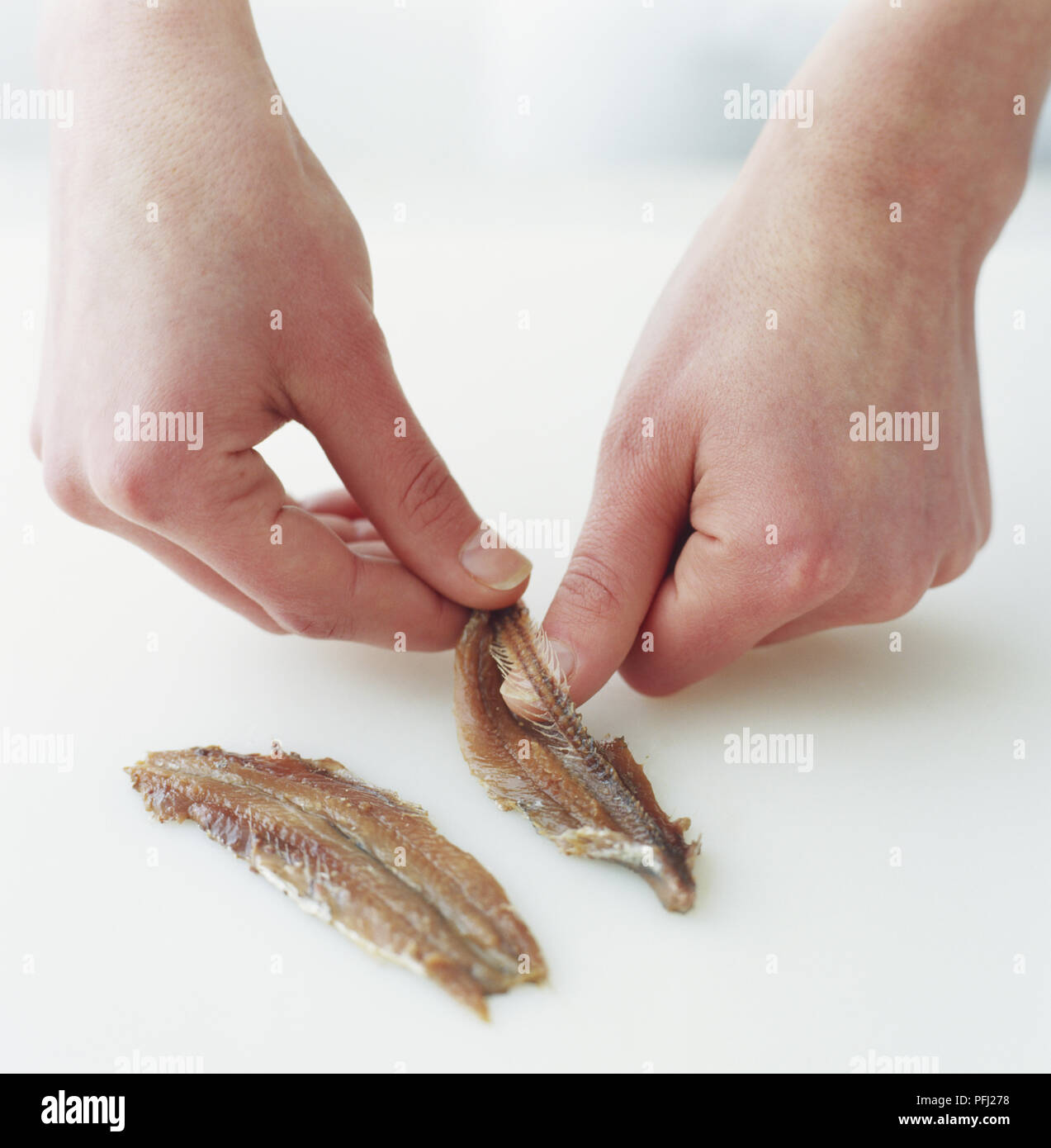 Using thumb to separate anchovy flesh from spine Stock Photo - Alamy