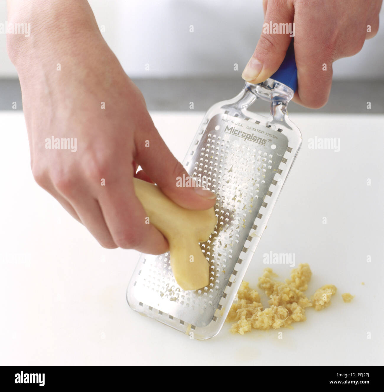 Using a hand-held metal grater to grate a piece of ginger Stock Photo ...