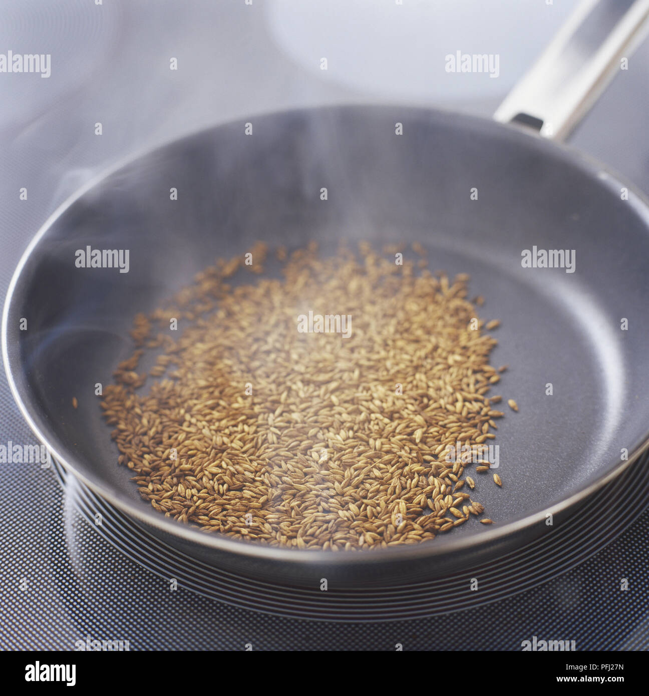 Fennel seeds dry-roasting in a frying pan Stock Photo - Alamy