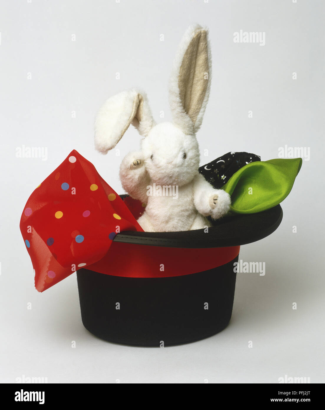 A top hat standing upside down containing a toy rabbit and various ...