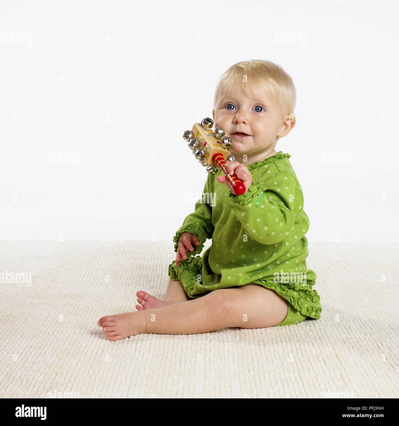 Baby girl holding wooden rattle Stock Photo - Alamy